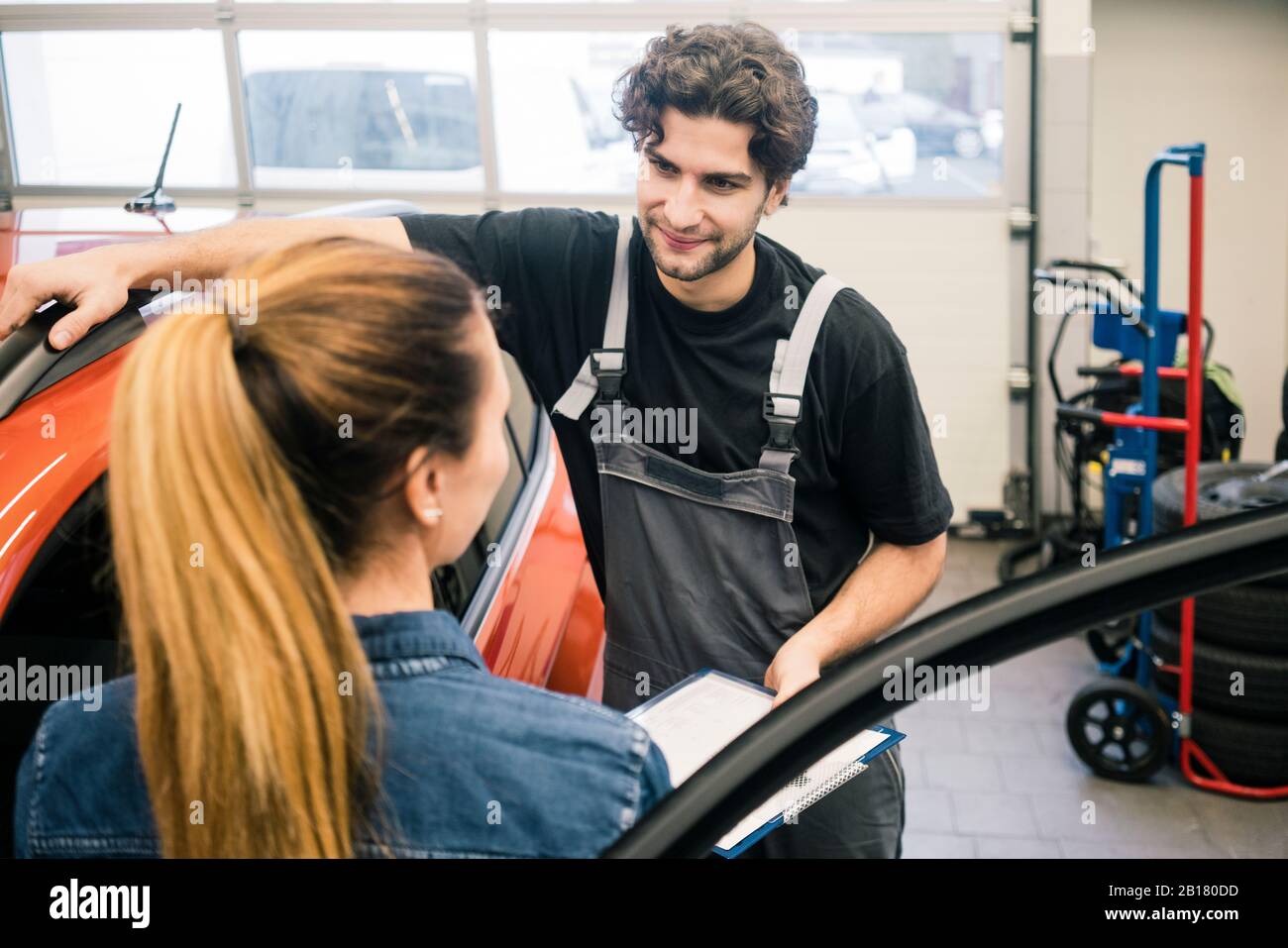 Car mechanic talking to client in workshop Stock Photo - Alamy