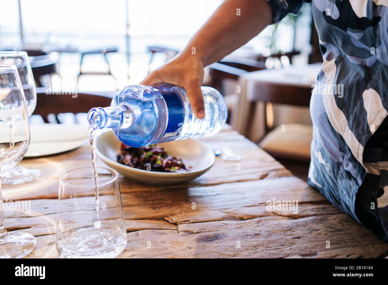 Woman pouring water into glass in restaurant Stock Photo - Alamy