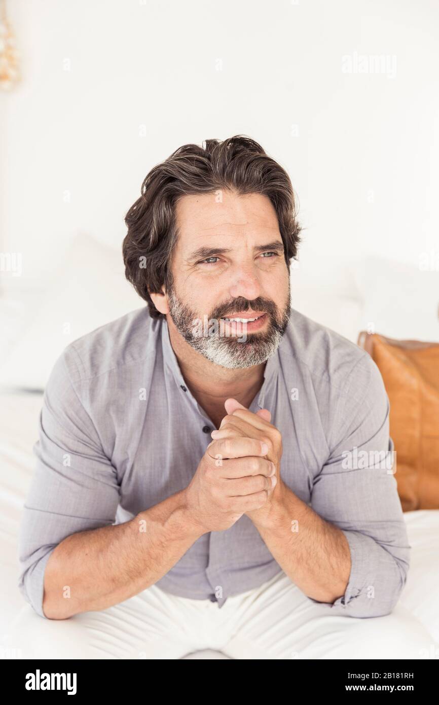 Portrait of bearded man sitting on bed Stock Photo - Alamy