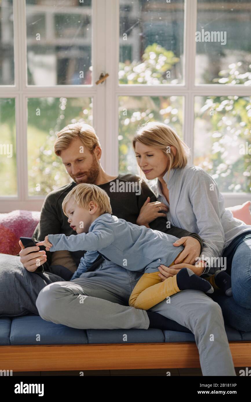 Family using cell phone in sunroom at home Stock Photo - Alamy