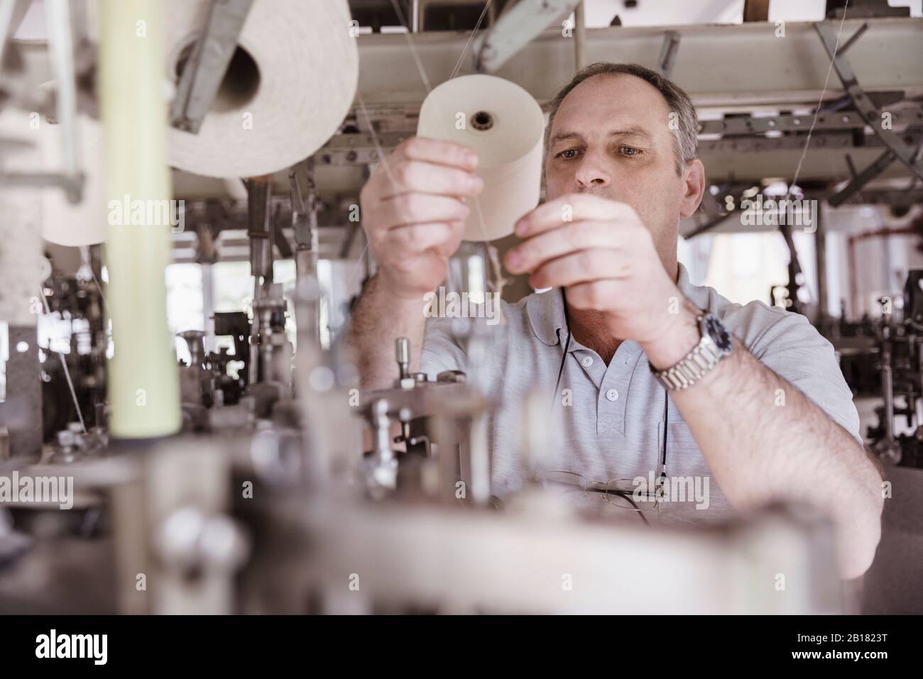 Man working with cotton reel in a textile factory Stock Photo - Alamy