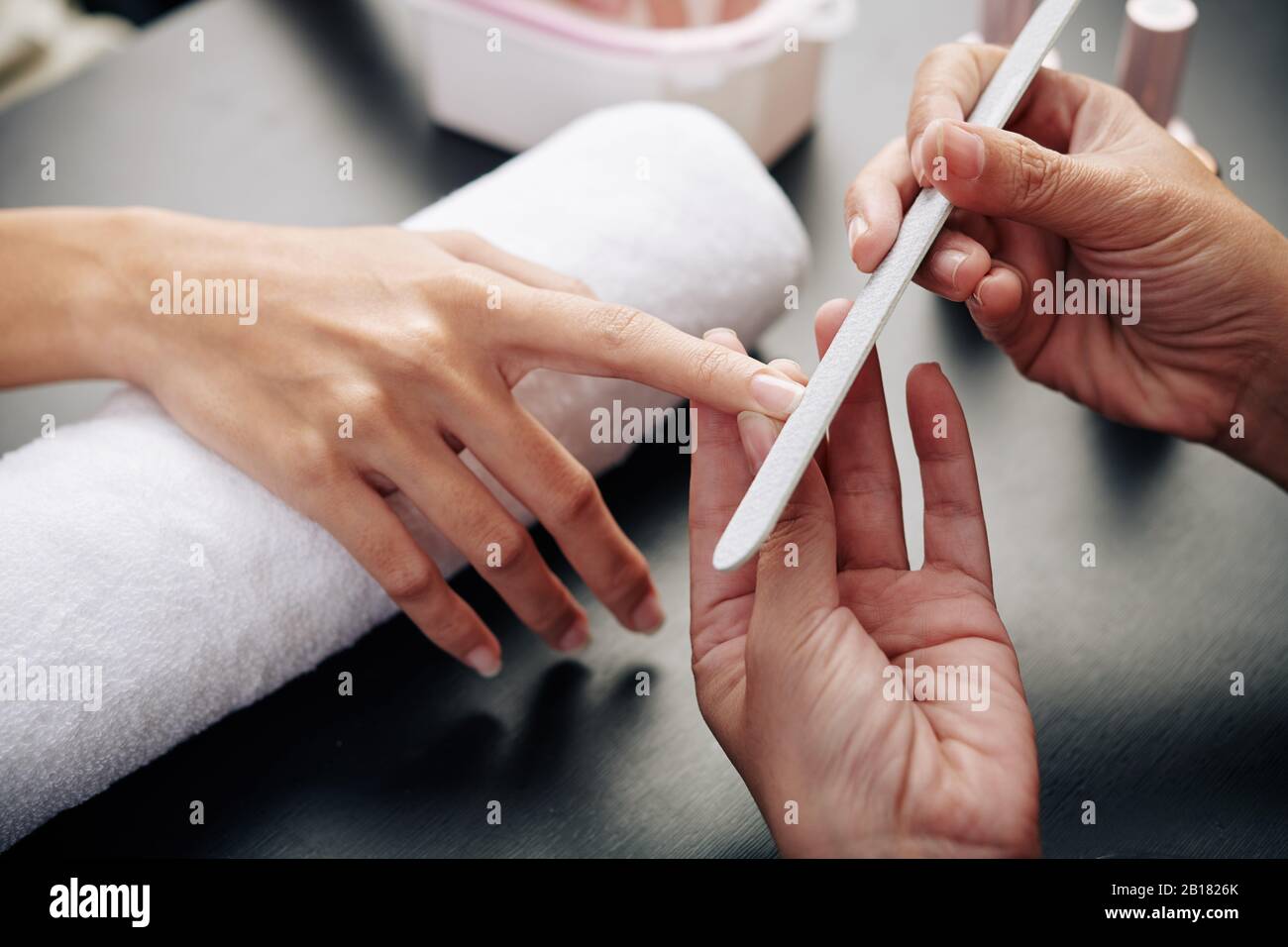 Process of manicurist filing nails of female client, view from above ...