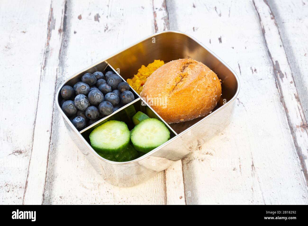 Lunch box with cucumber slices, blueberries and bun with lentil paste ...