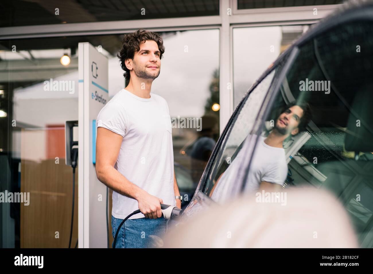 Man charging an electric car at a station Stock Photo - Alamy