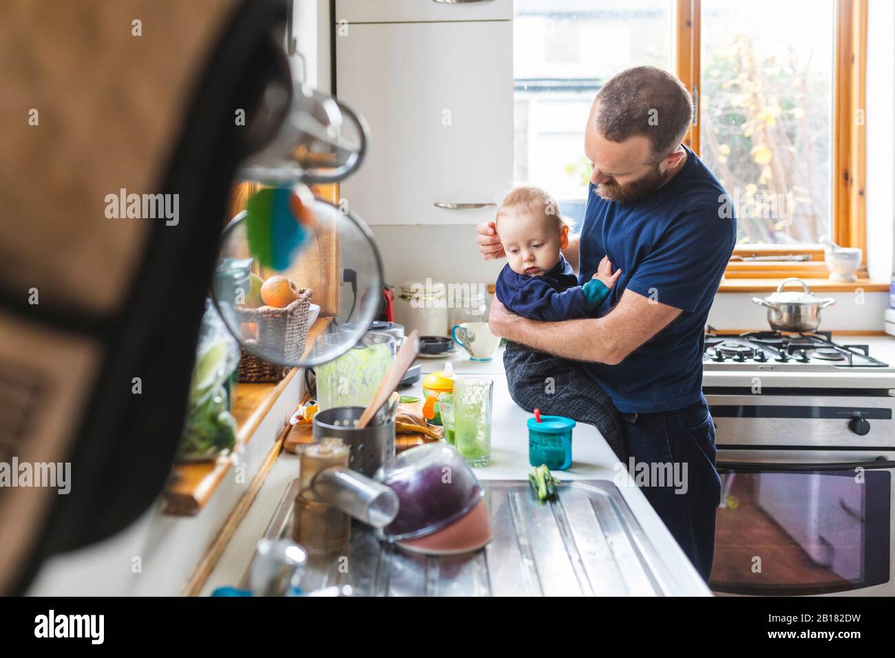 Man in the kitchen preparing food and cuddling his son Stock Photo - Alamy
