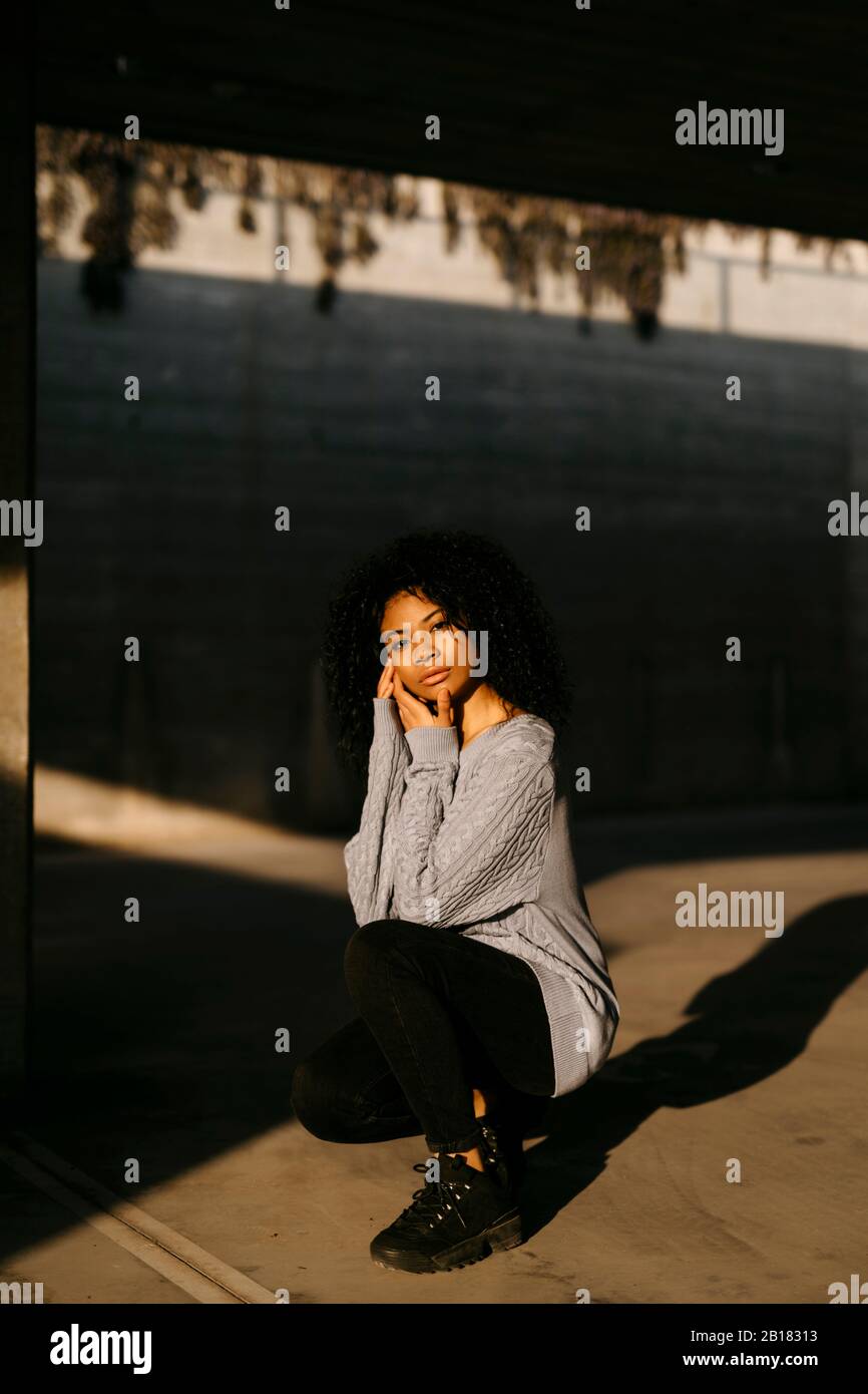 Portrait of a beautiful young woman crouching in sunlight Stock Photo ...