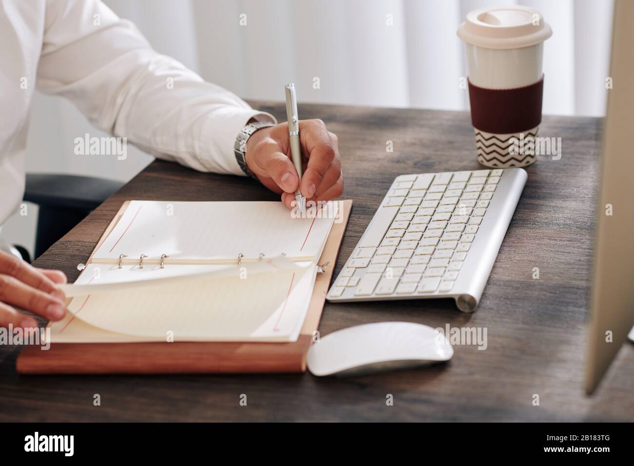 Businessman reading document or article on computer screen and writing ...
