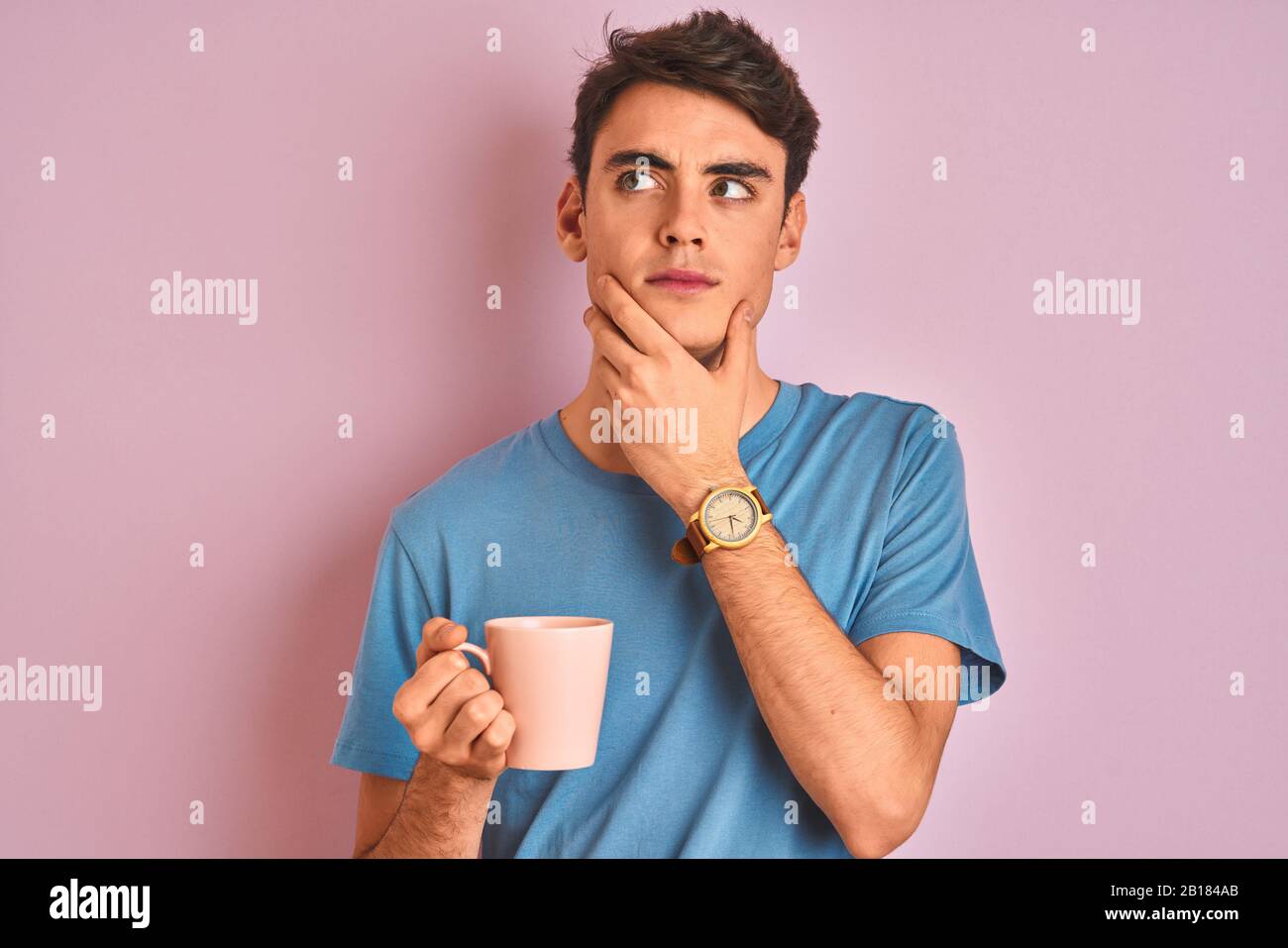 Teenager boy drinking a cup of coffee over isolated pink background ...