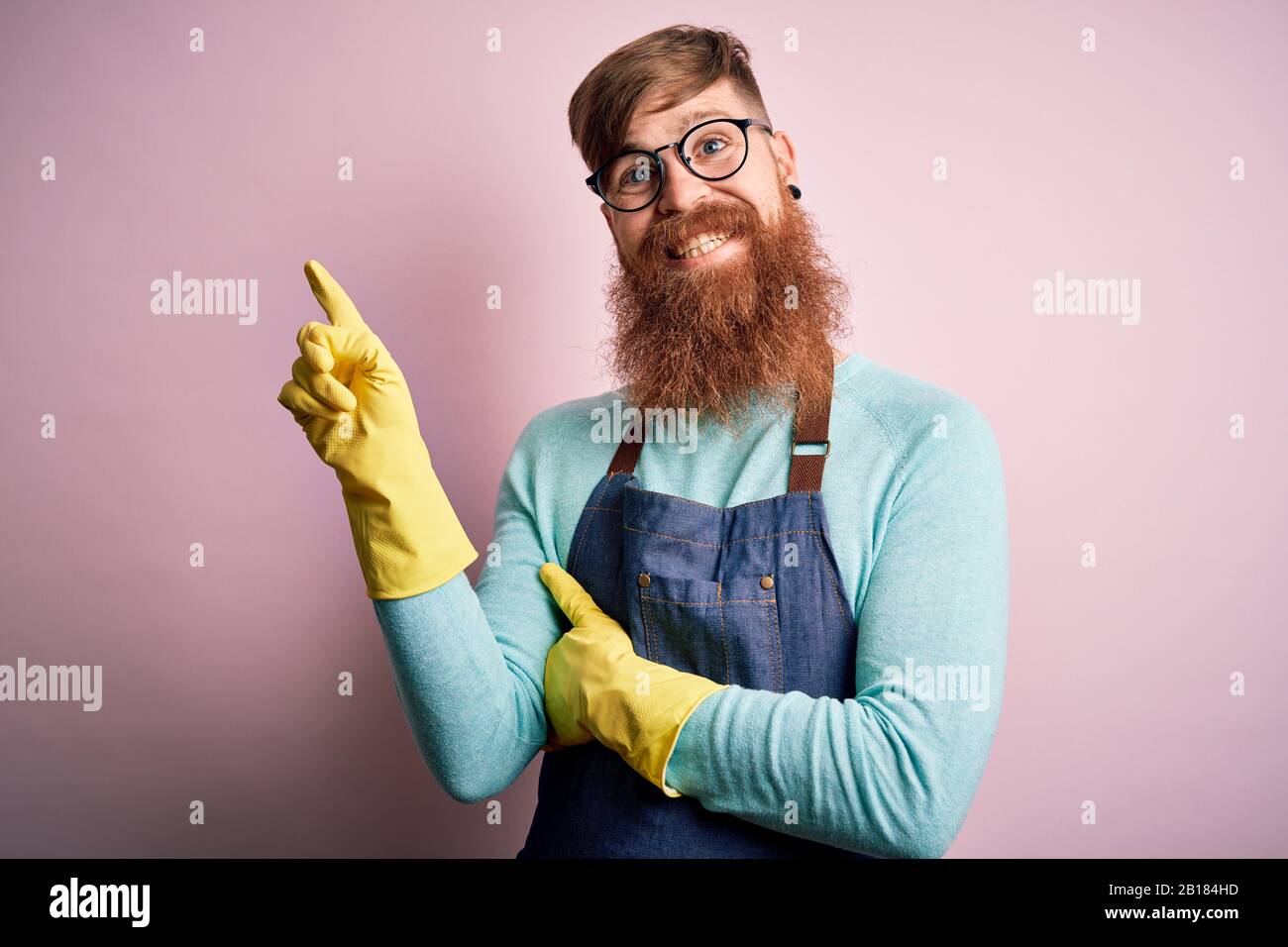 Irish redhead housekeeping man with beard wearing apron and washing ...