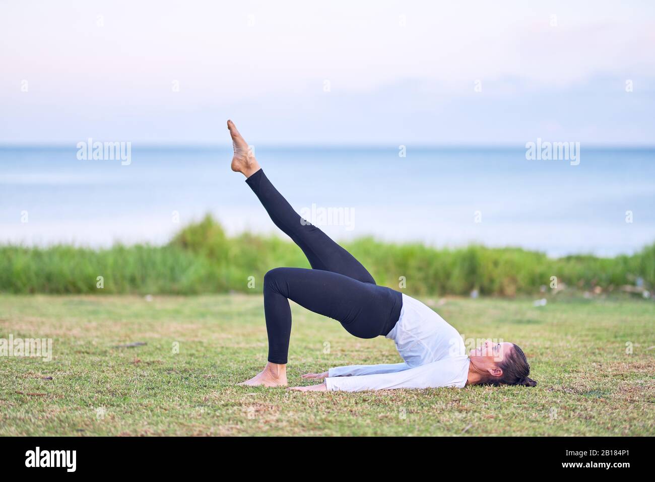 Young beautiful sportwoman practicing yoga. Coach teaching bridge pose ...
