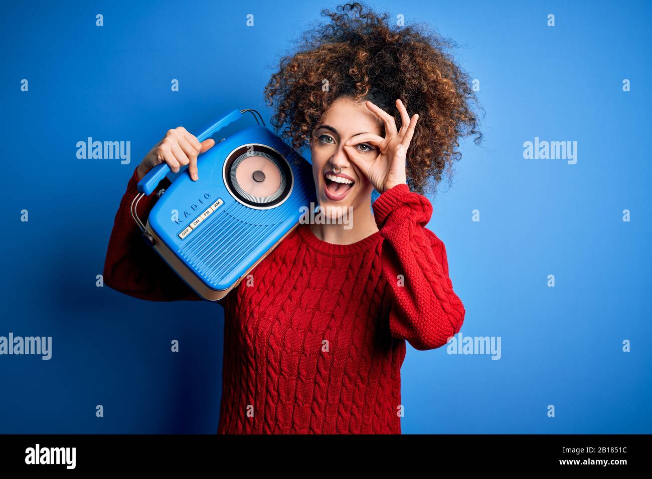 Young beautiful woman with curly hair and piercing listening to music ...