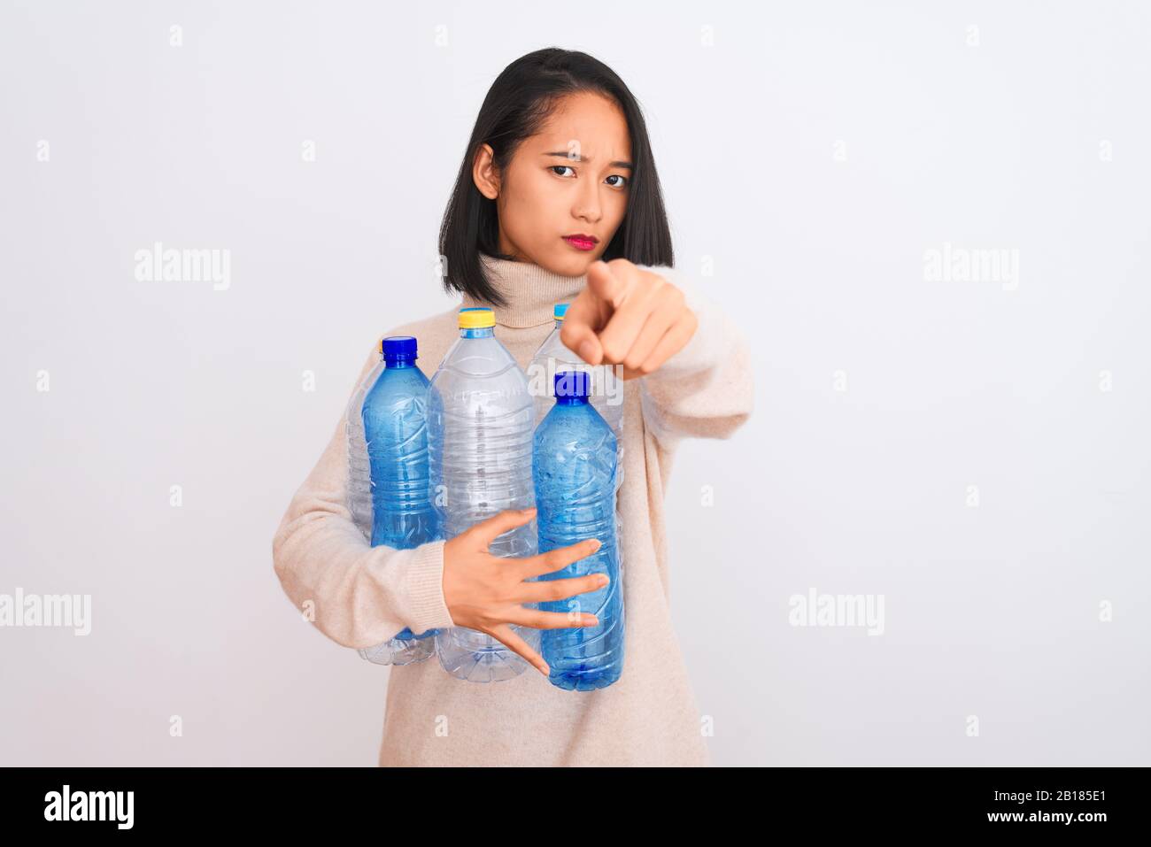 Young beautiful chinese woman recycling plastic bottles over isolated ...