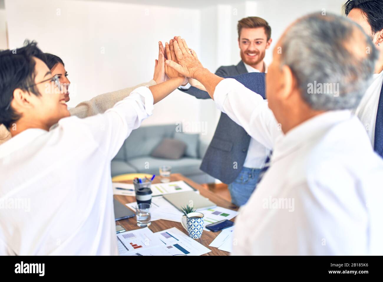 Group of business workers standing with hands together at the office ...