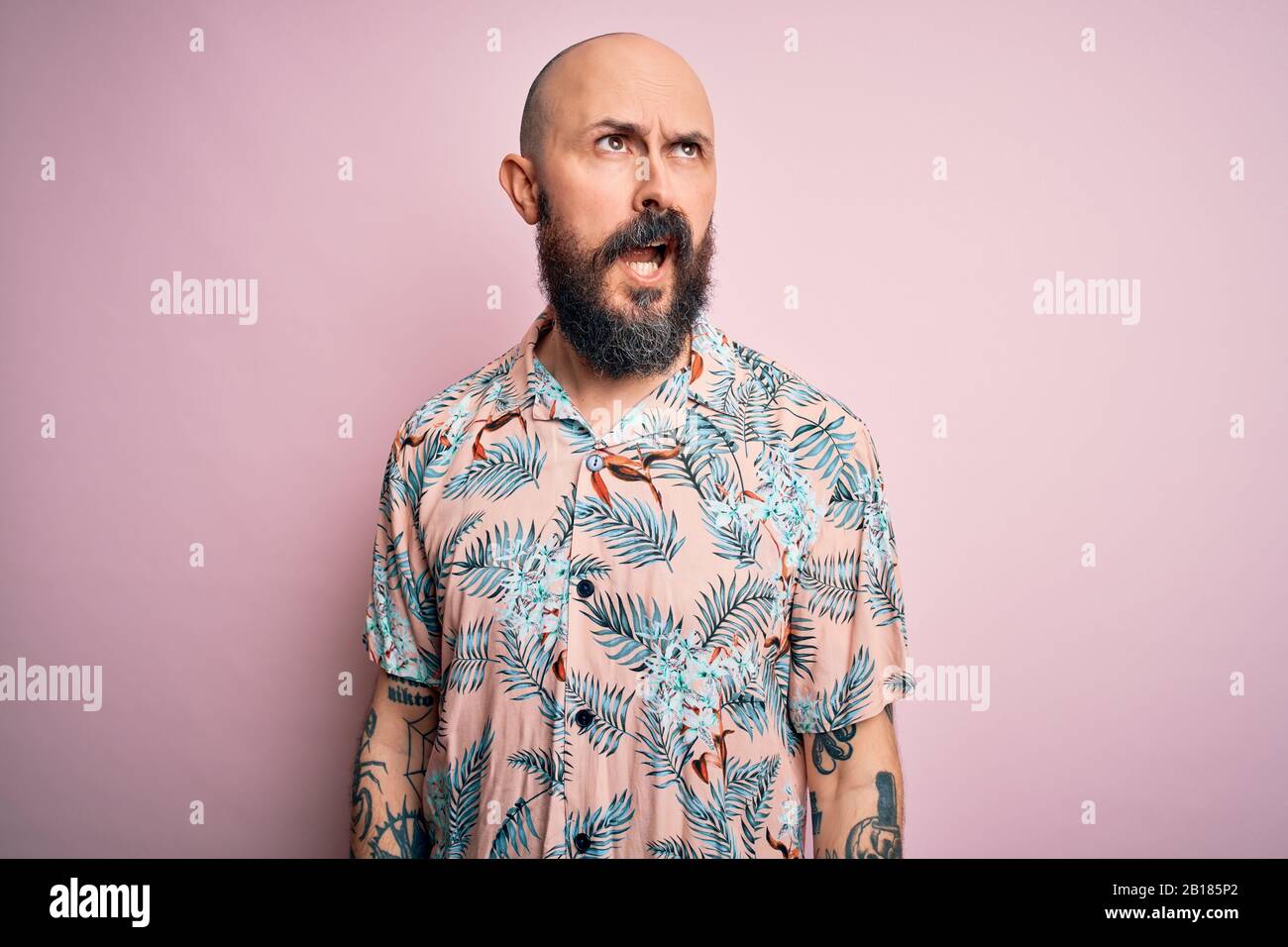 Handsome bald man with beard and tattoo wearing casual floral shirt ...