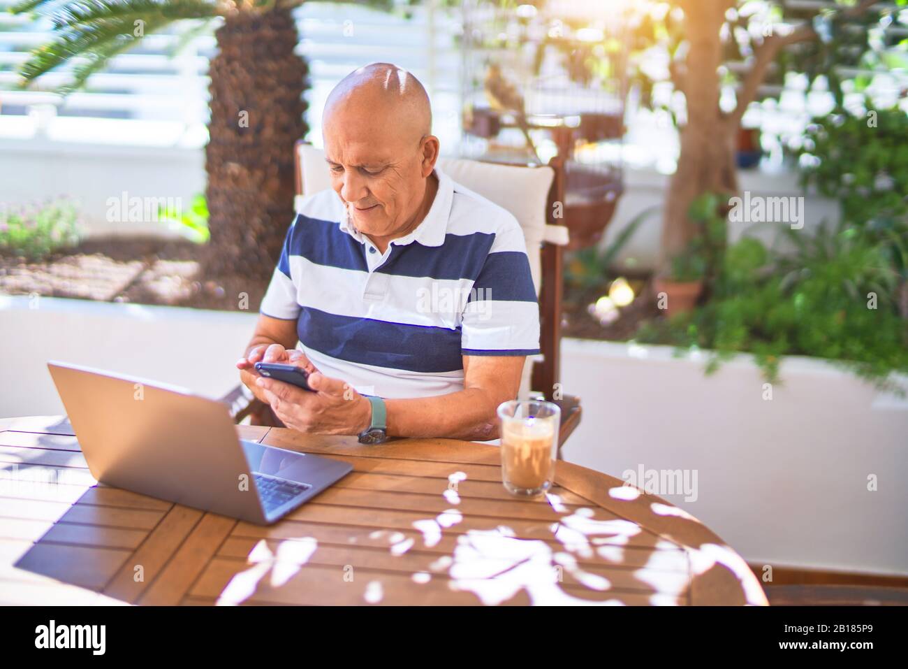 Senior handsome man smiling happy and confident. Sitting using laptop ...