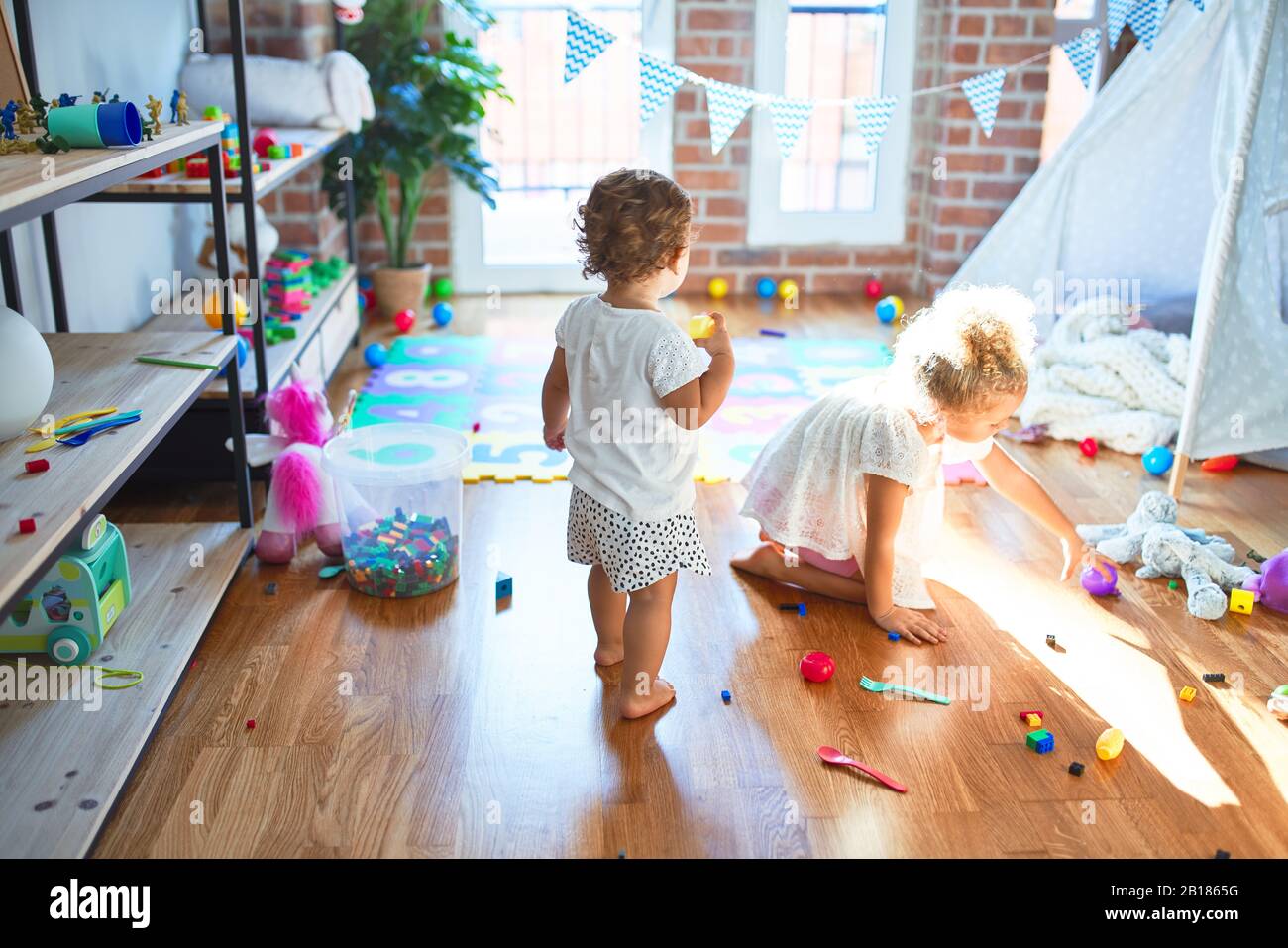 Beautiful toddlers playing around lots of toys at kindergarten Stock ...