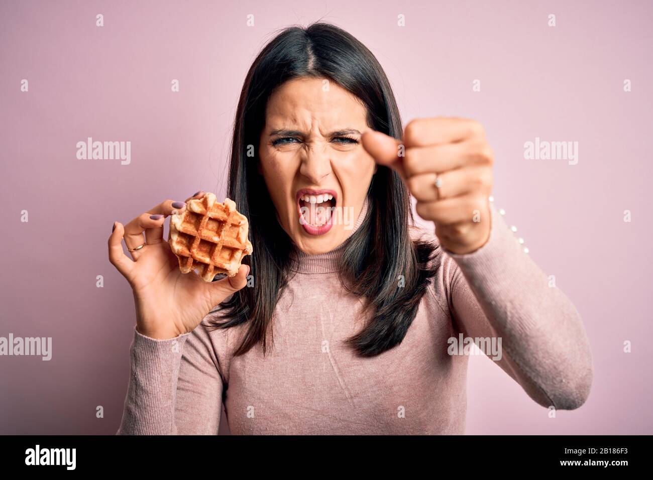 Young brunette woman with blue eyes eating sweet waffle for breakfast ...