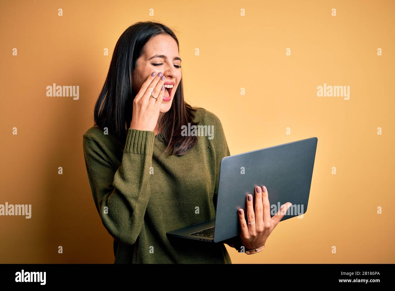 Young brunette woman with blue eyes working using computer laptop over ...