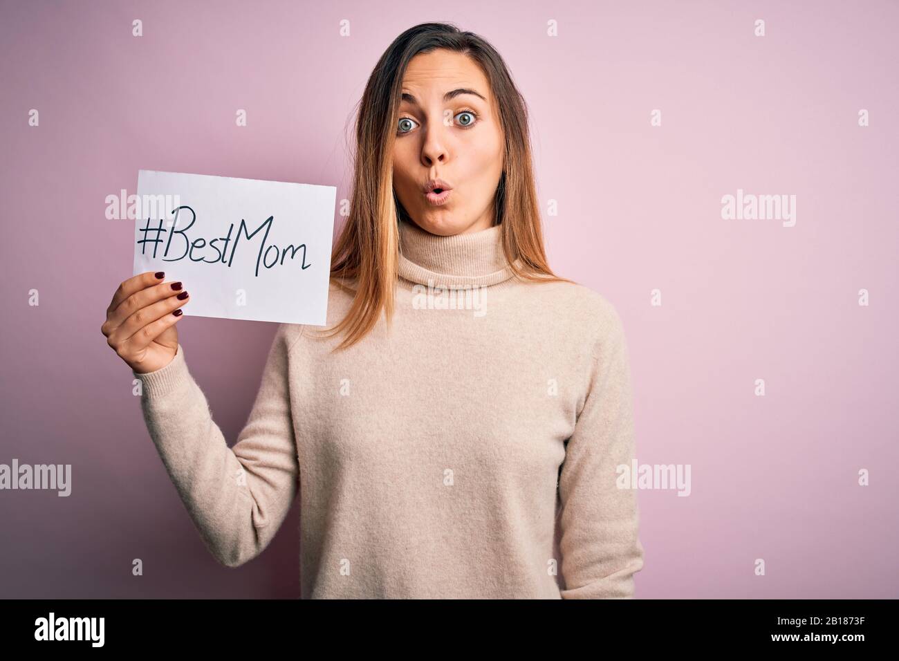 Young beautiful woman holding paper with best mom message celebrating ...