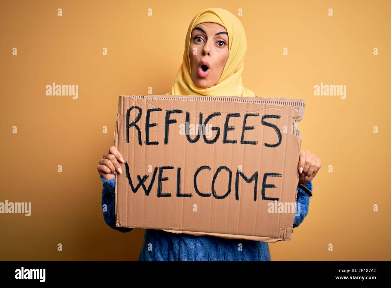 Beautiful arab woman wearing islamic hijab holding banner with refugees ...