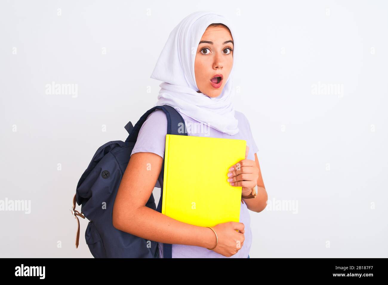 Arab student girl wearing hijab and backpack holding book over isolated ...