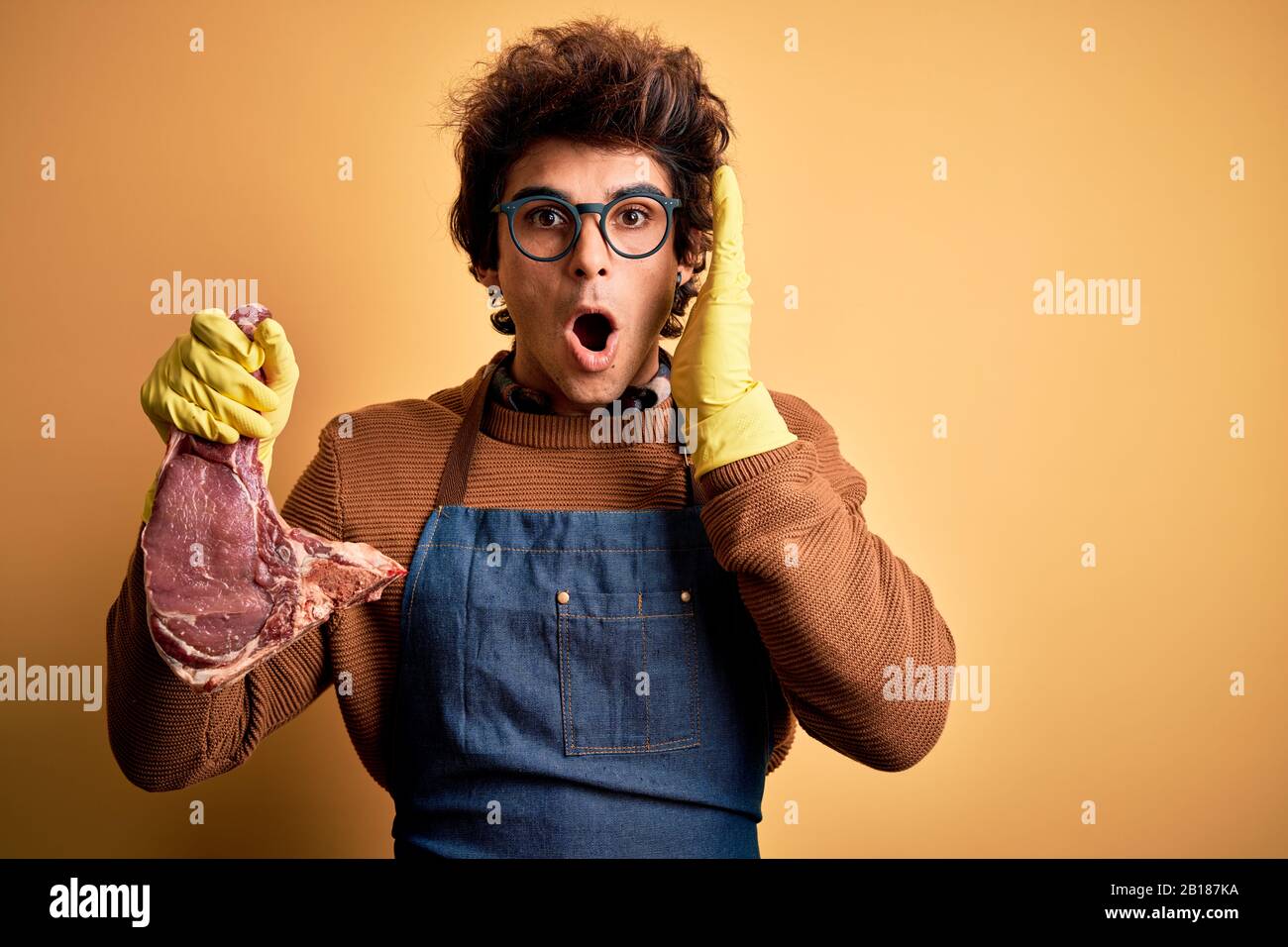 Young handsome butcher man holding meet steak standing over isolated ...