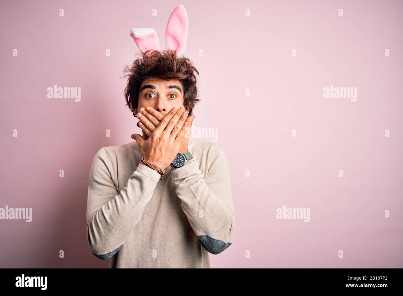 Young handsome man holding easter rabbit ears standing over isolated ...