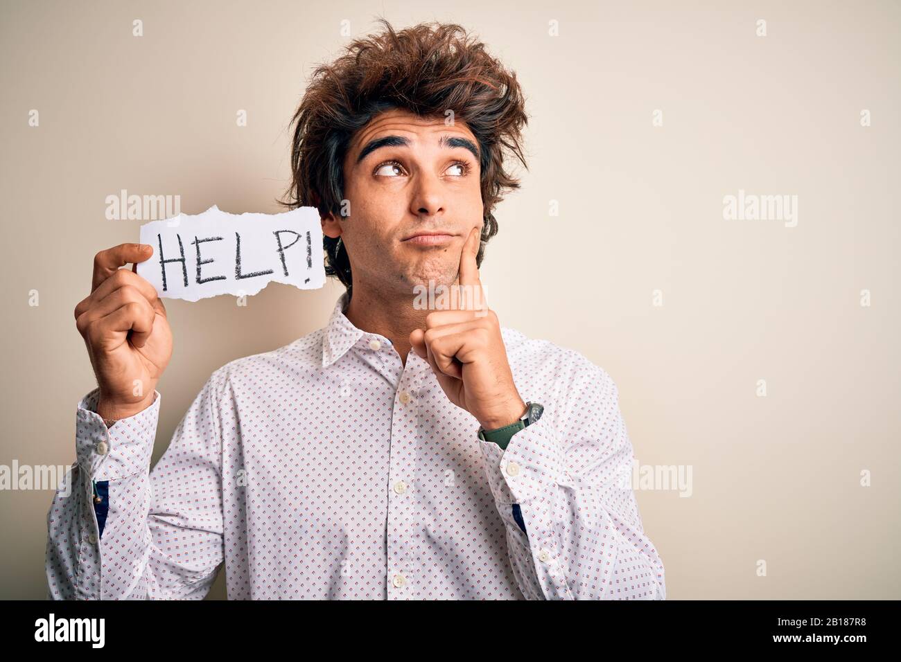Young handsome man holding paper with help message over isolated white ...