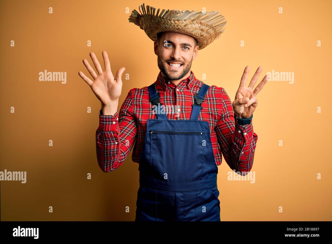 Young rural farmer man wearing bib overall and countryside hat over ...