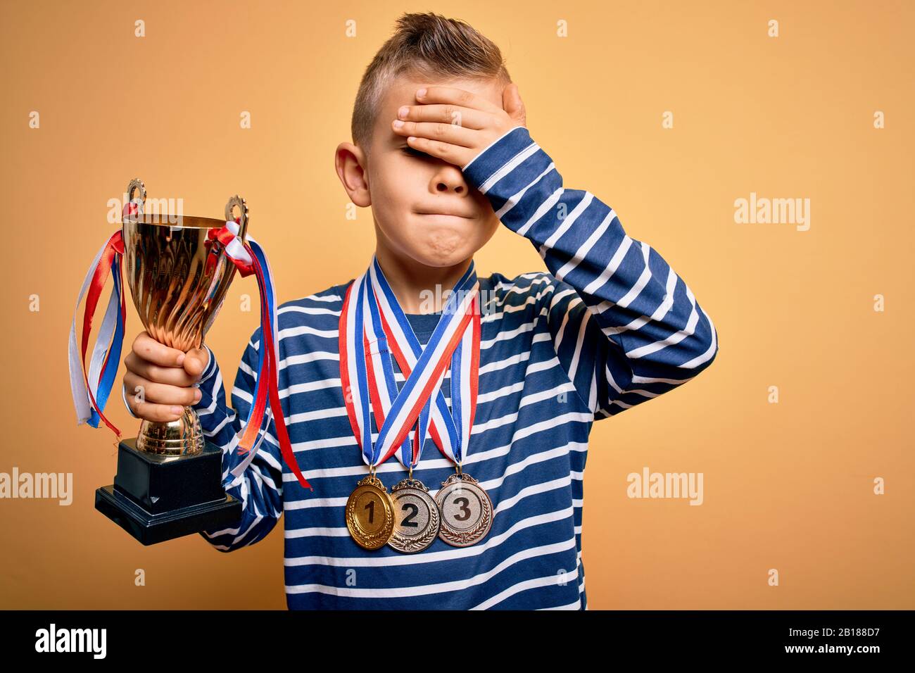Young little caucasian kid wearing winner medals and victory award ...
