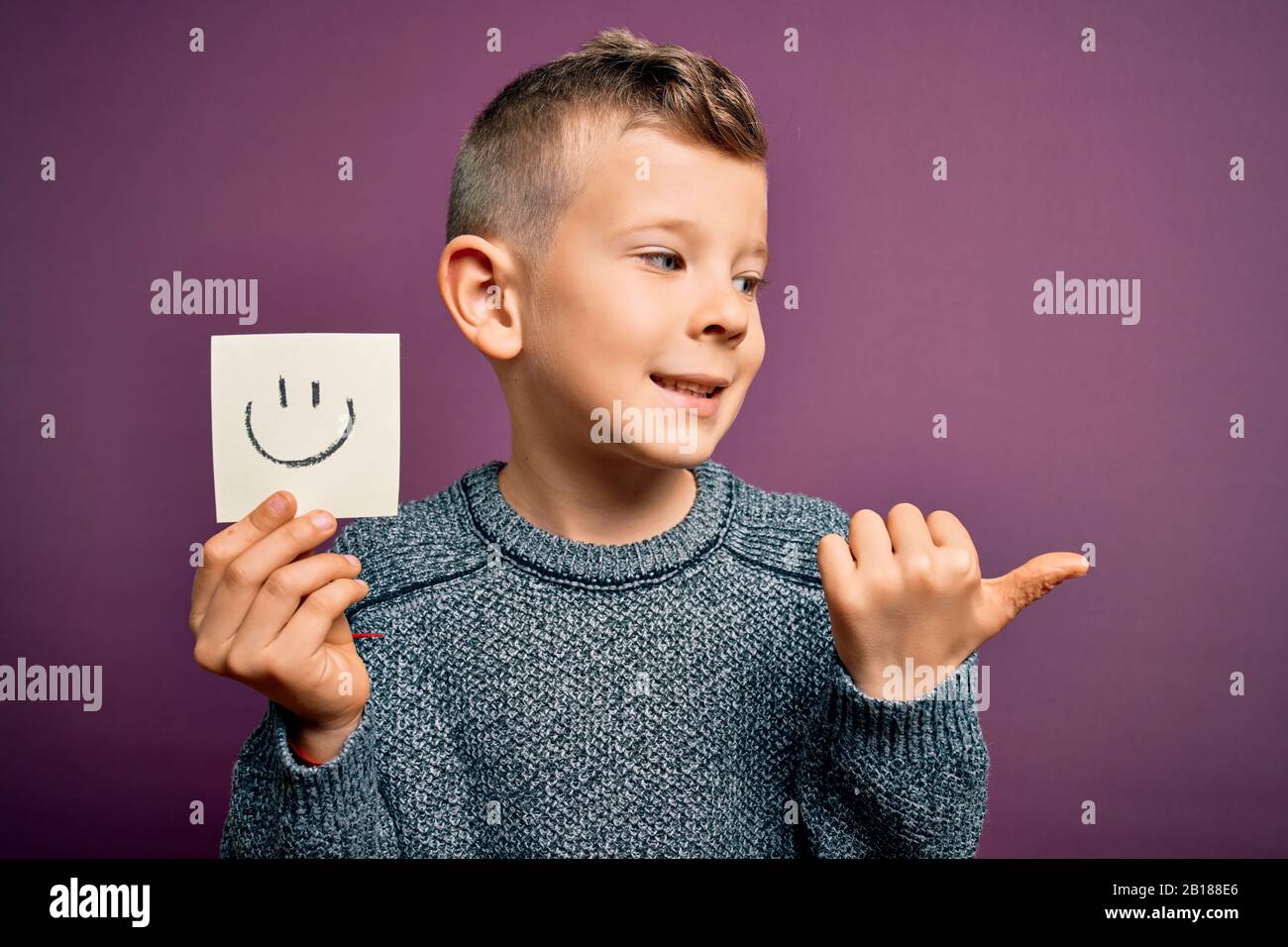 Young little caucasian kid showing smiley face on a paper note as happy ...