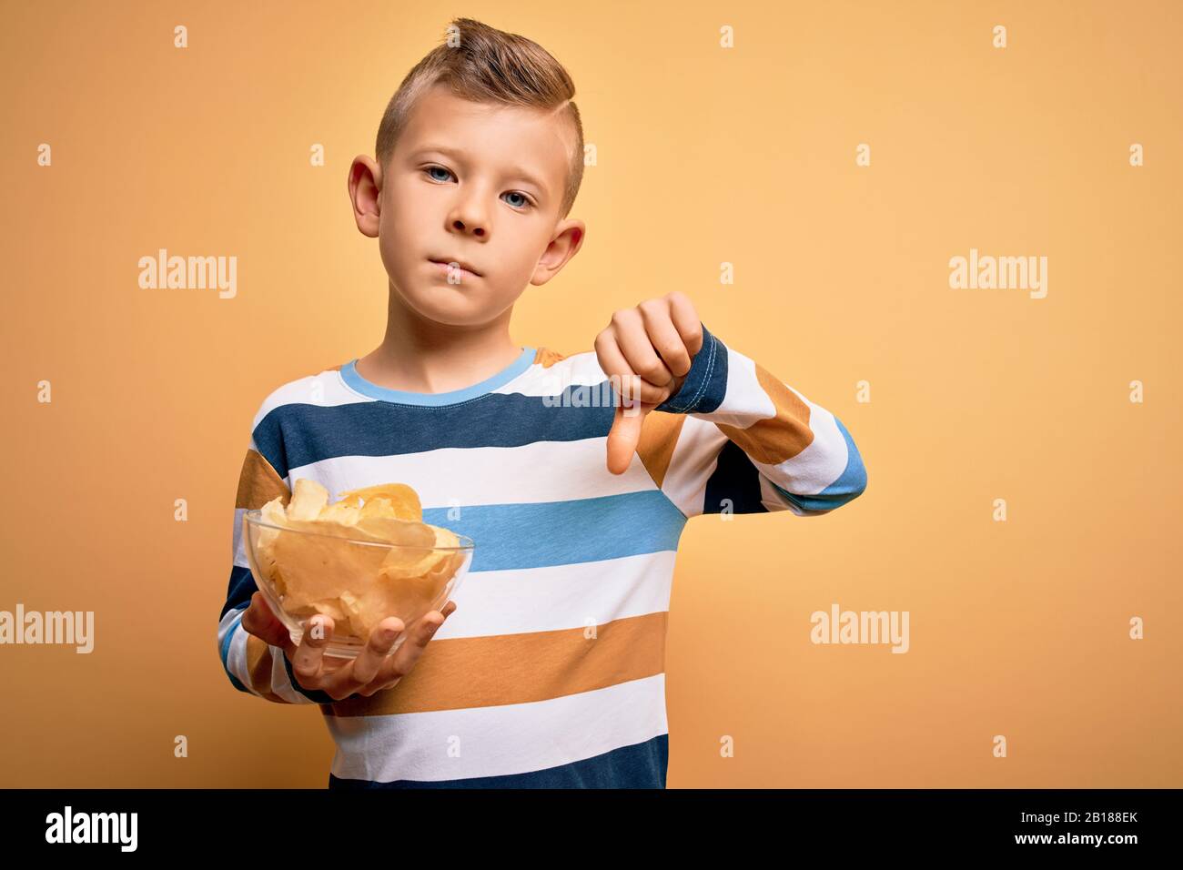 Young little caucasian kid eating unheatlhy potatoes crisps chips over ...