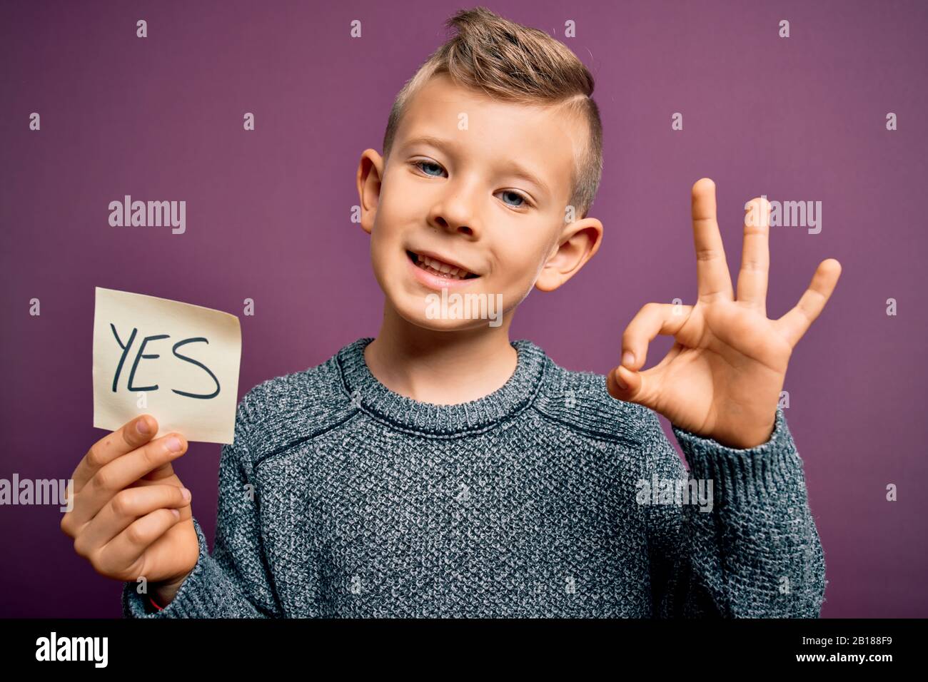 Young little caucasian kid showing YES word on a paper note as positive ...