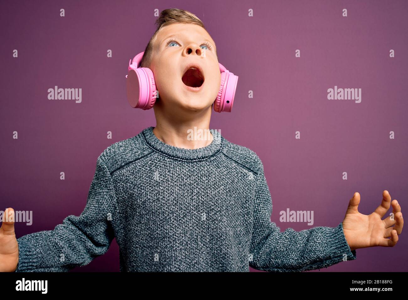 Young little caucasian kid wearing headphones listening to music over ...