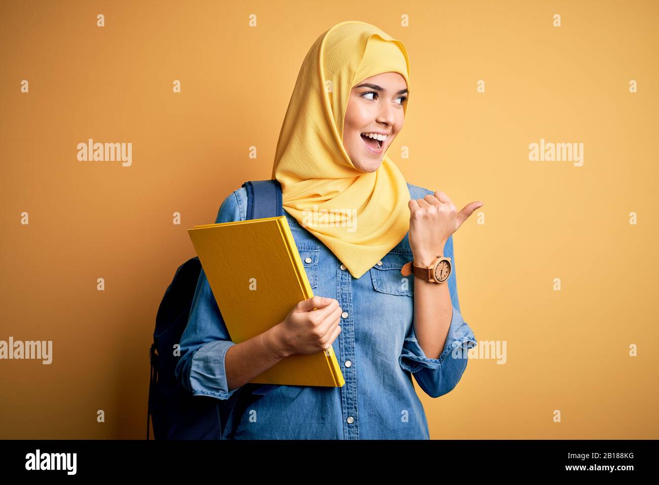 Young student girl wearing muslim hijab and backpack holding book over ...
