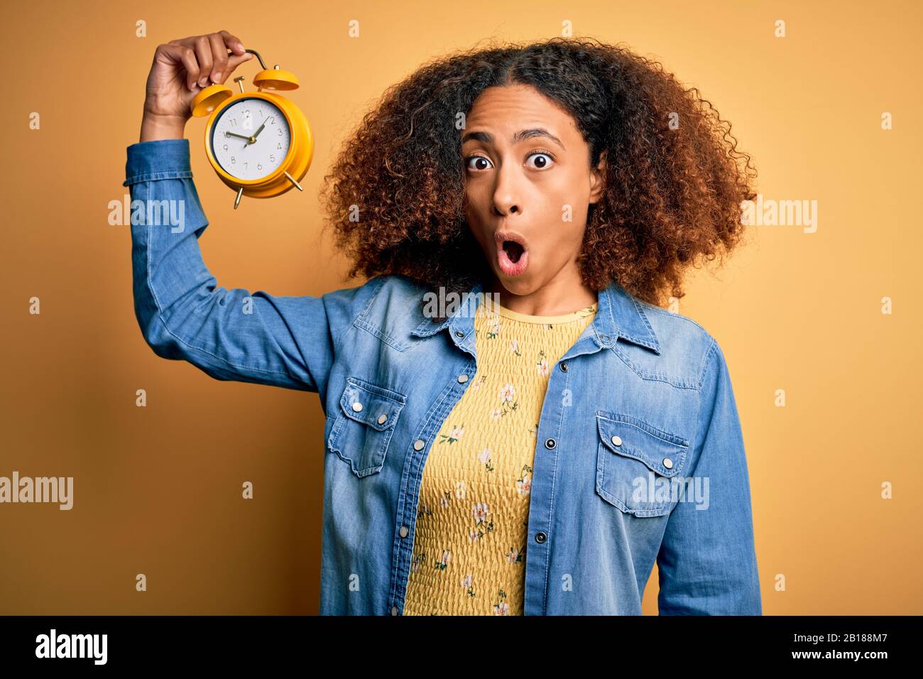 Young african american woman with afro hair holding vintage alarm clock ...