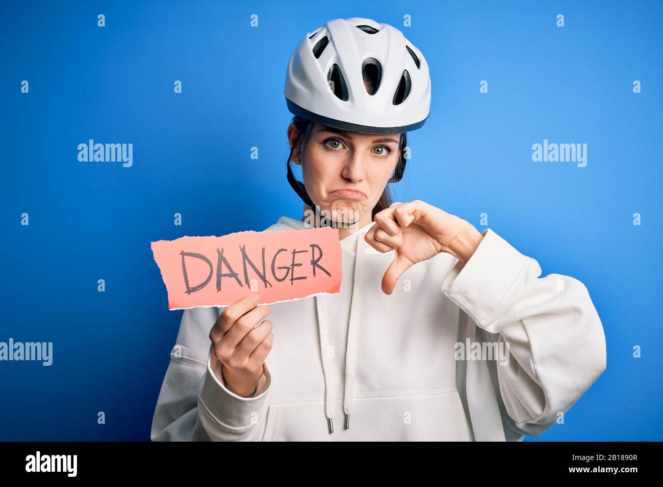 Young beautiful redhead cyclist woman wearing bike helmet holding ...