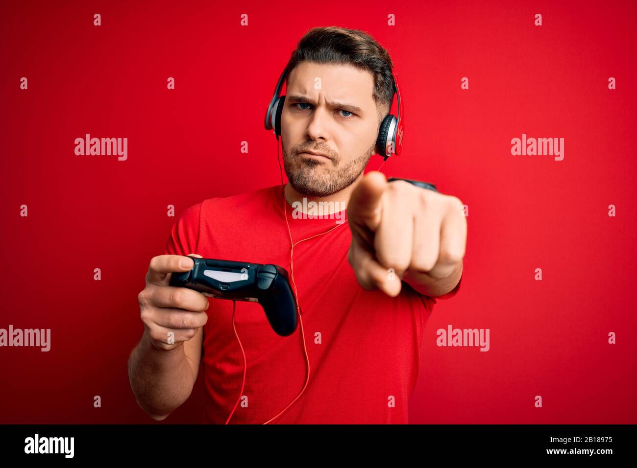 Young gamer man with blue eyes playing video games using gamepad ...