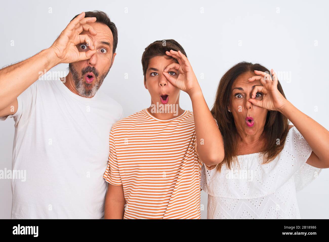 Family of three, mother, father and son standing over white isolated ...