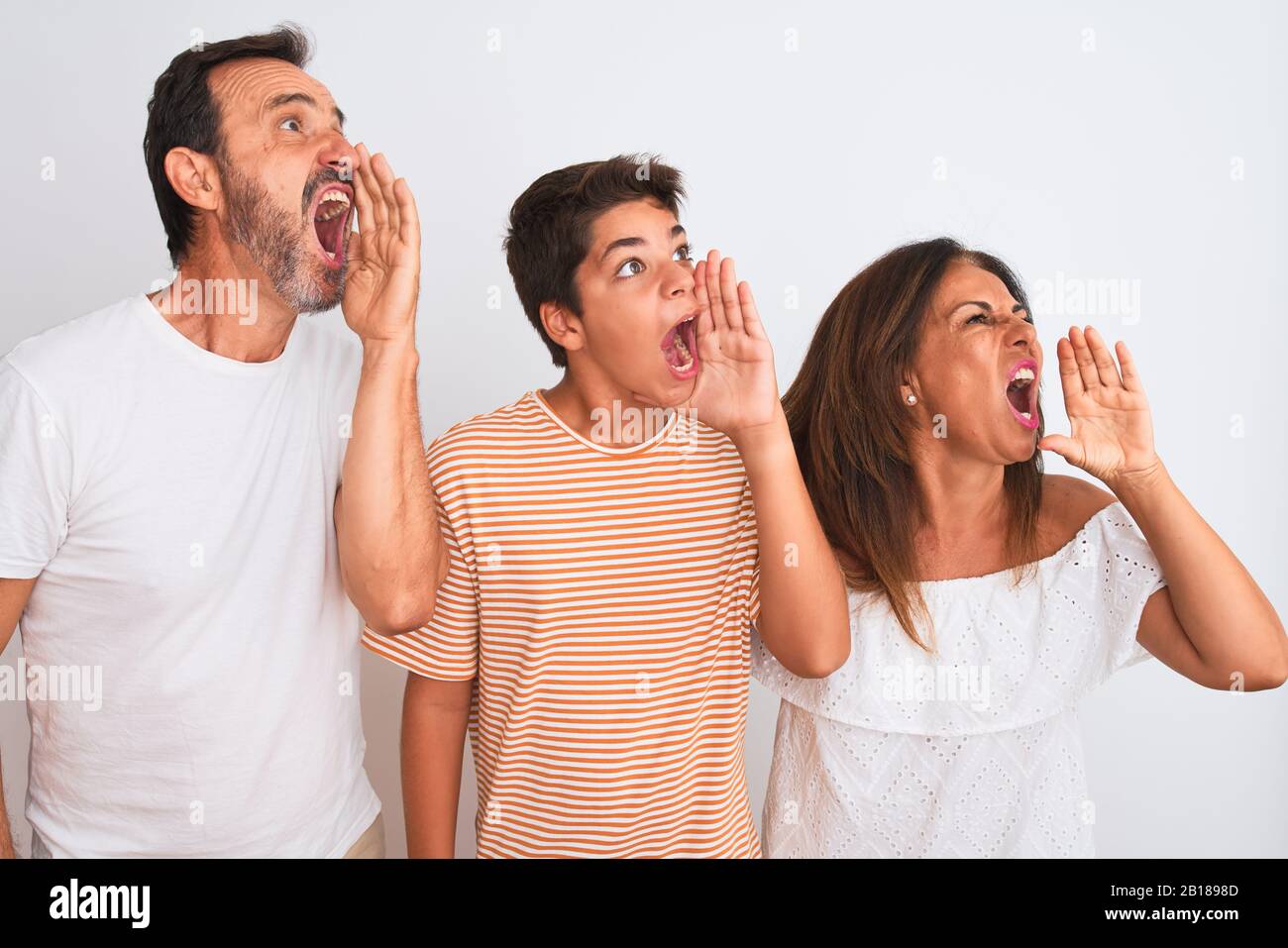 Family of three, mother, father and son standing over white isolated ...