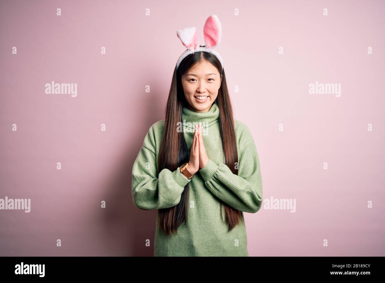 Young asian woman wearing cute easter bunny ears over pink background ...