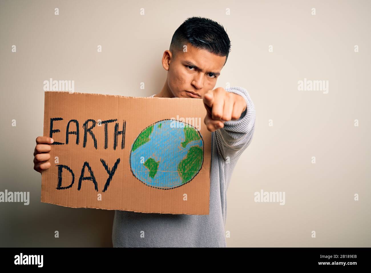 Young handsome latin man holding banner asking for earth and enviroment ...