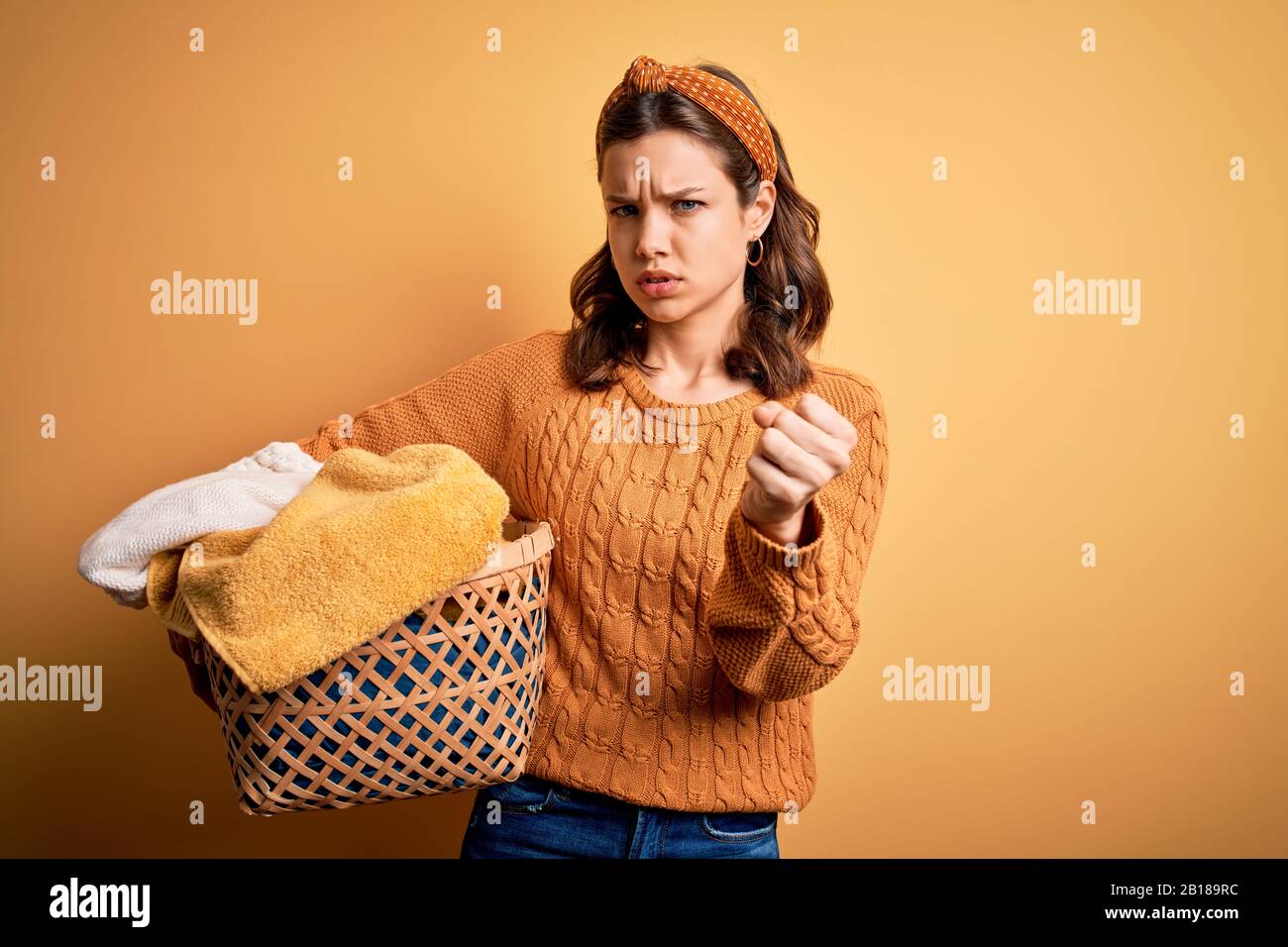 Young blonde girl doing housework chores holding laundry wicker basket ...