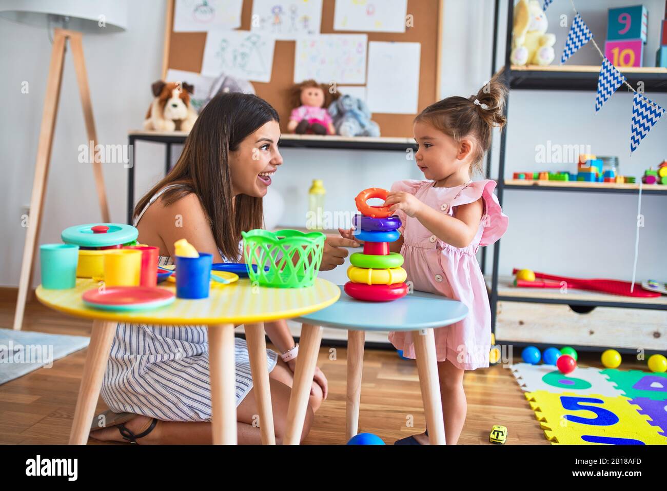 Young beautiful teacher and toddler building pyramid using hoops on the ...