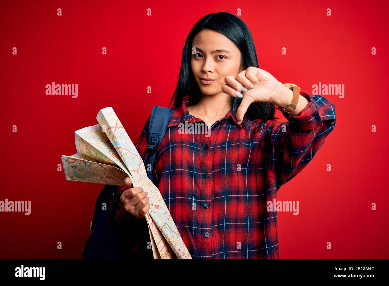 Young beautiful chinese tourist woman holding city map over isolated ...