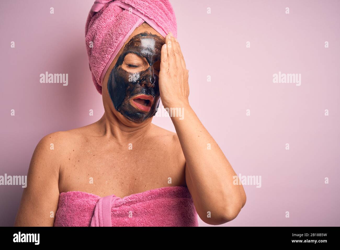 Middle age brunette woman wearing beauty black face mask over isolated ...