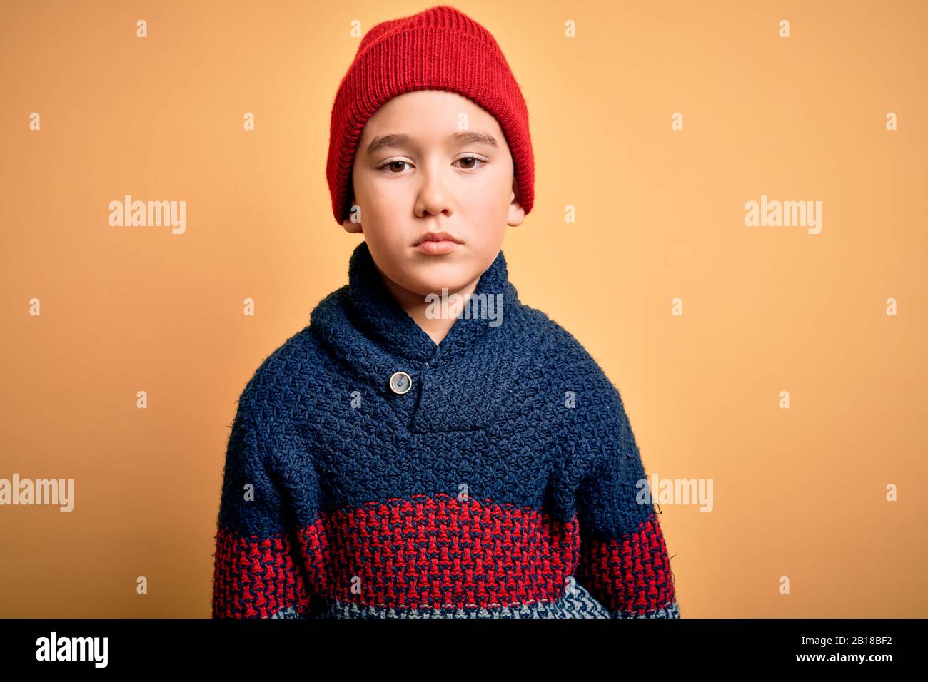 Young little boy kid wearing wool cap and winter sweater over yellow ...