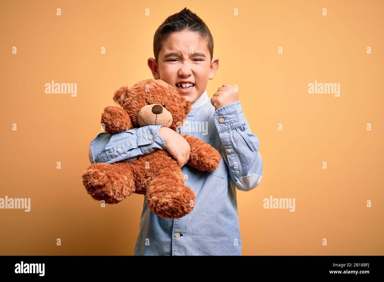 Young little boy kid hugging teddy bear stuffed animal over yellow ...