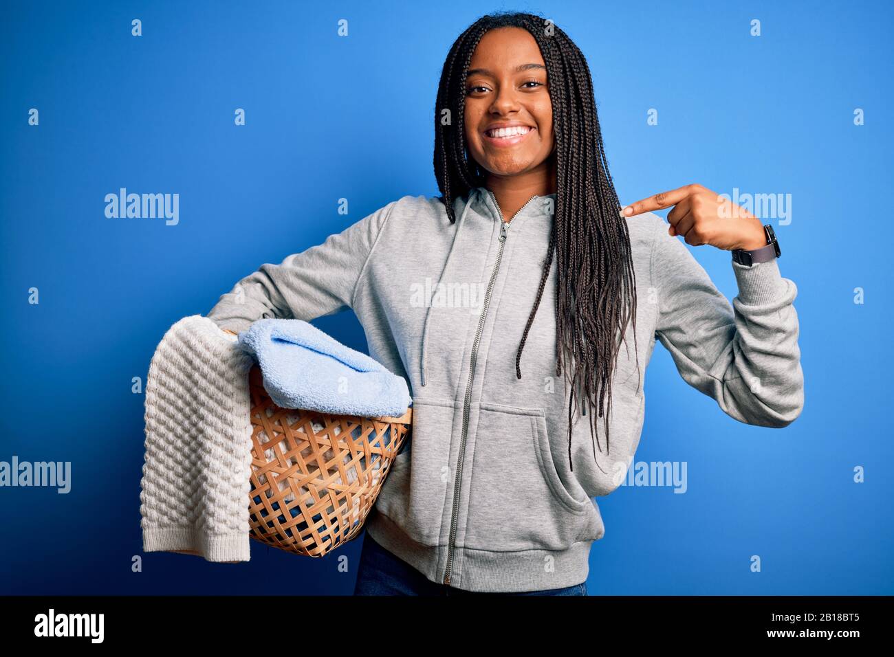 Young african american girl doing domestic housework holding laundry ...