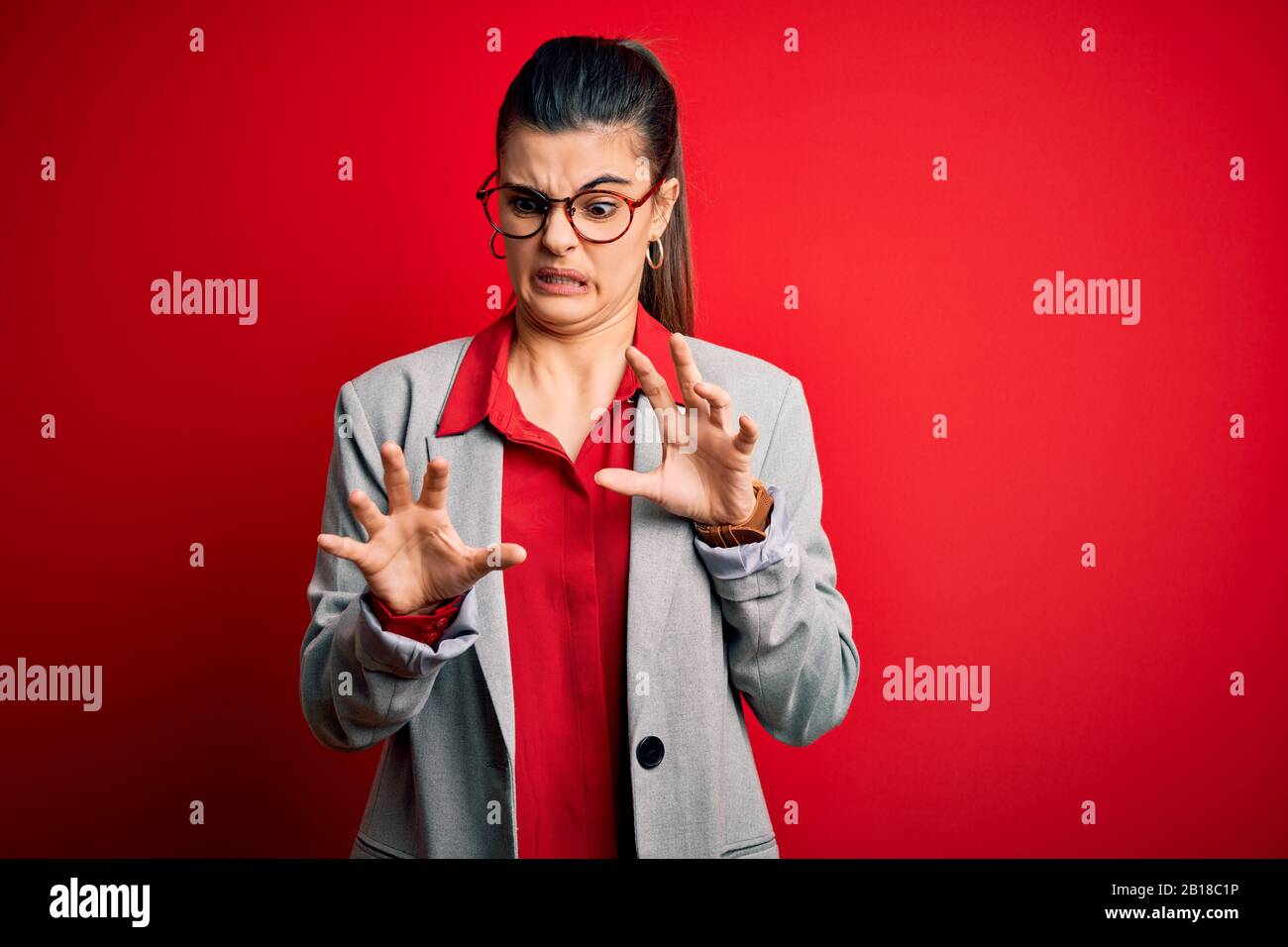 Young beautiful brunette businesswoman wearing jacket and glasses over ...